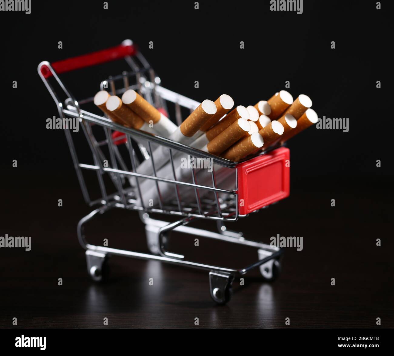 Cigarettes in shopping cart on wooden table on dark background Stock ...