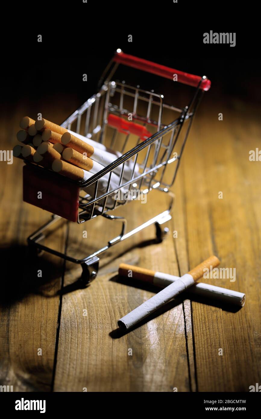 Cigarettes in shopping cart on wooden table on dark background Stock ...
