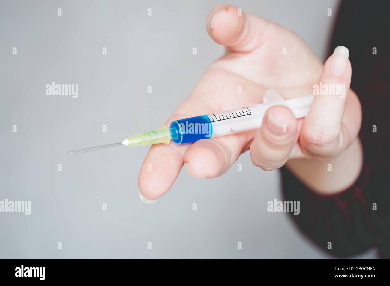 Womans hand holding a syringe Stock Photo - Alamy