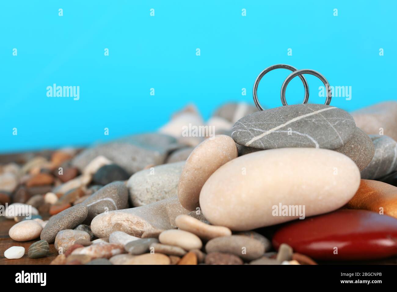 Wedding rings on rocks on blue background Stock Photo - Alamy