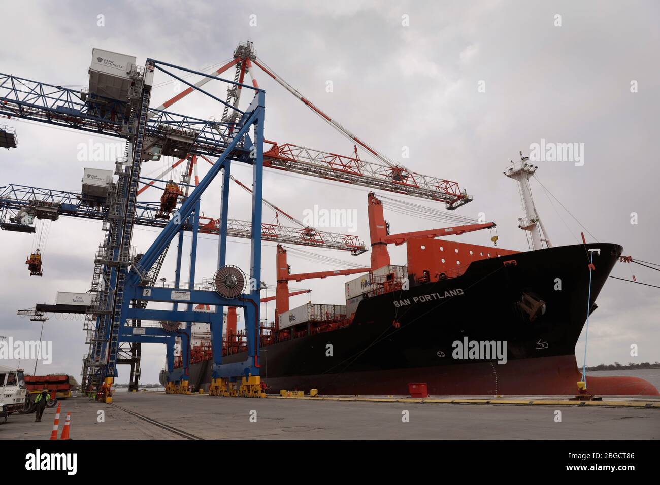 A cargo ship is offloaded by massive cranes at Penn Terminals in ...