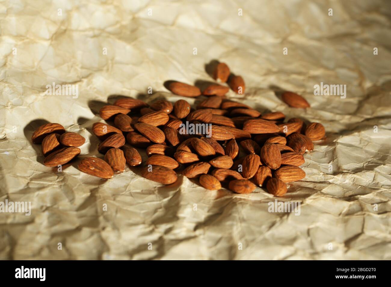 Almonds on old paper background Stock Photo - Alamy