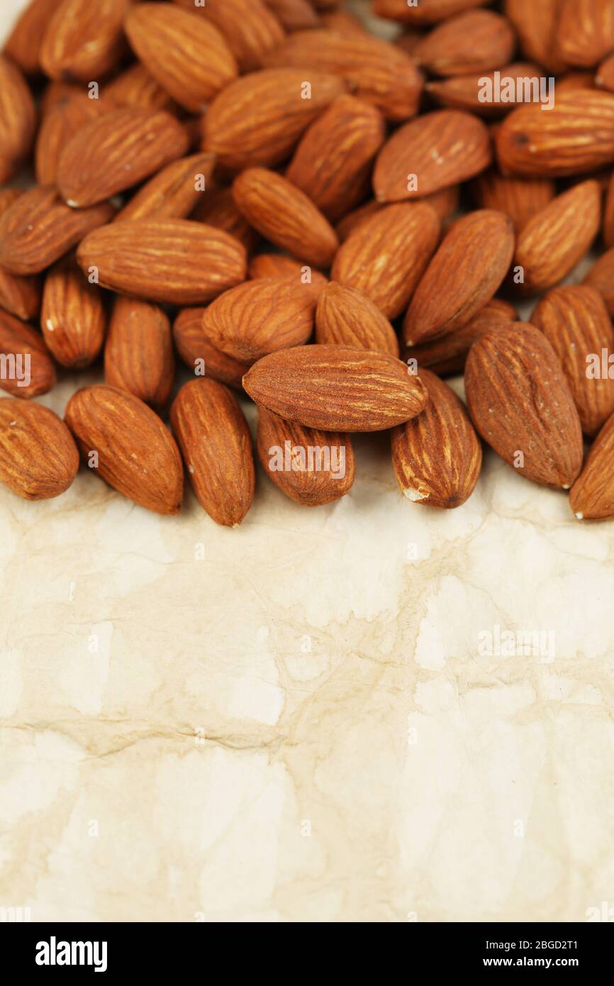 Almonds on old paper background Stock Photo - Alamy