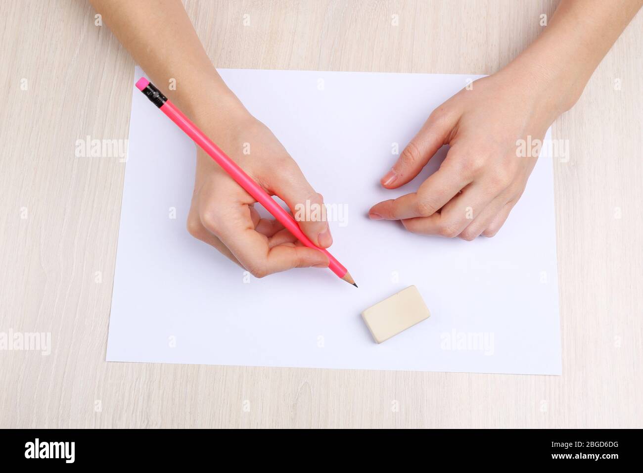 Human hands with pencil writing on paper and erase rubber on wooden ...