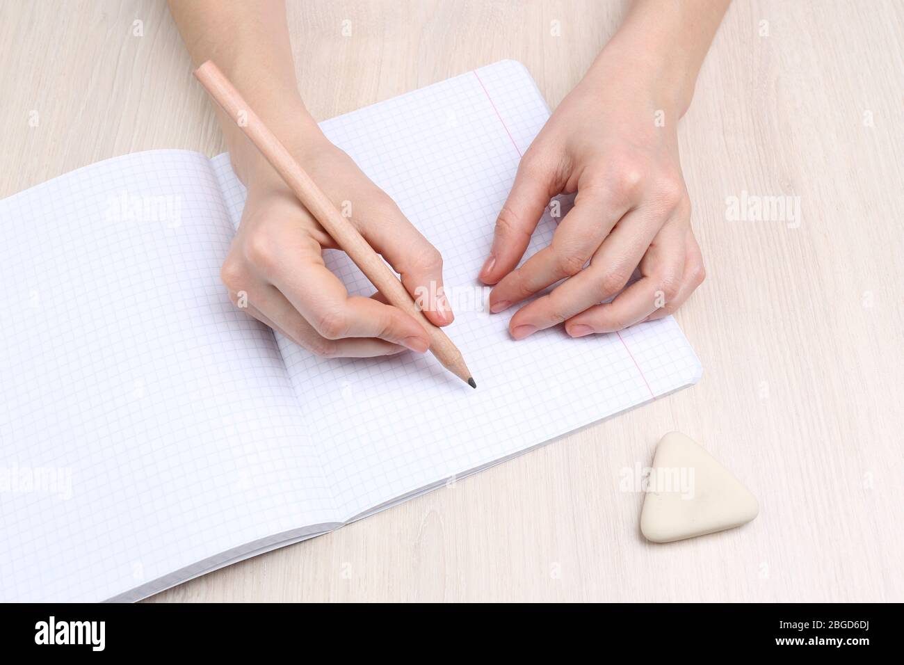 Human hands with pencil writing on paper and erase rubber on wooden ...