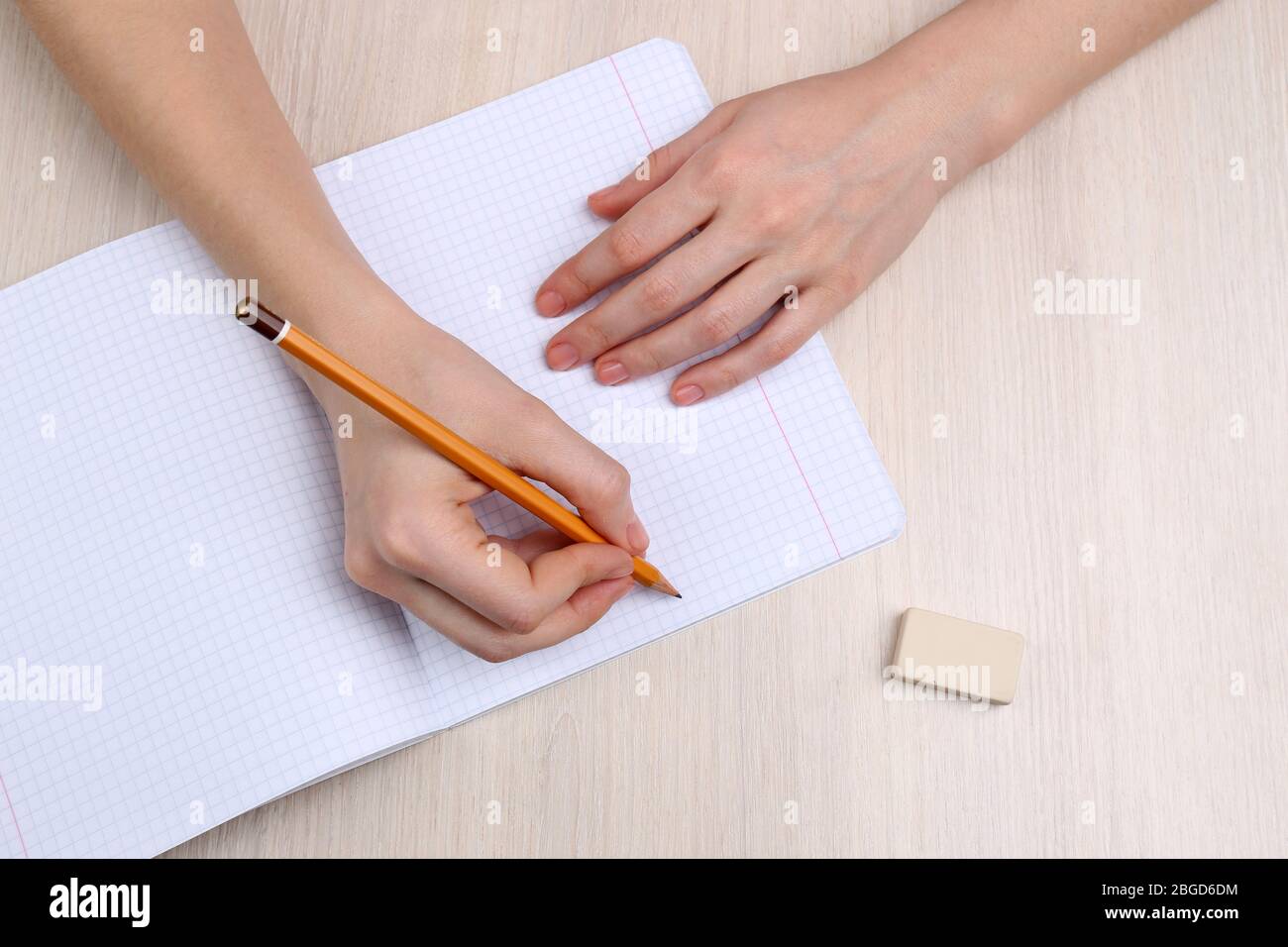 Human hands with pencil writing on paper and erase rubber on wooden ...