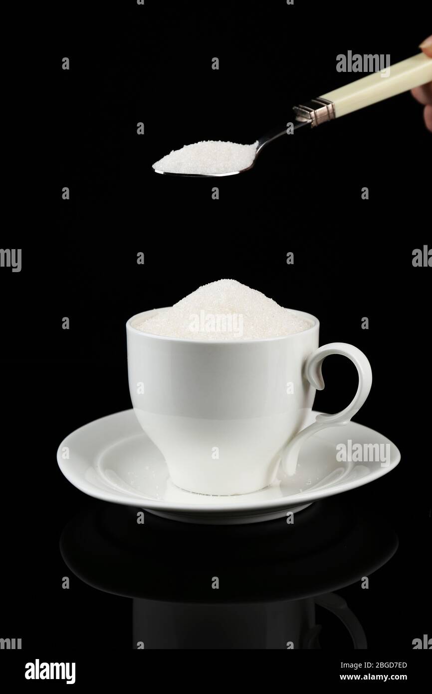 Sugar in cup isolated on black Stock Photo - Alamy