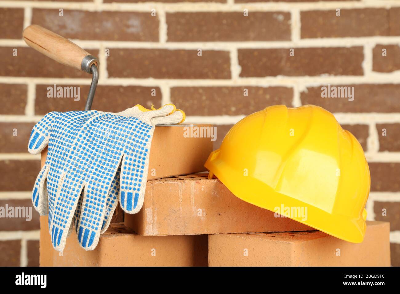 New bricks and building tools on brick wall background Stock Photo - Alamy