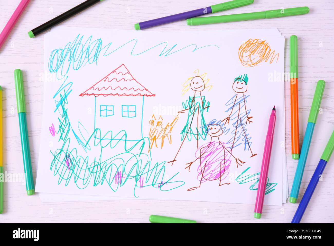 Kids drawing of family and colored pencils on wooden table Stock Photo ...