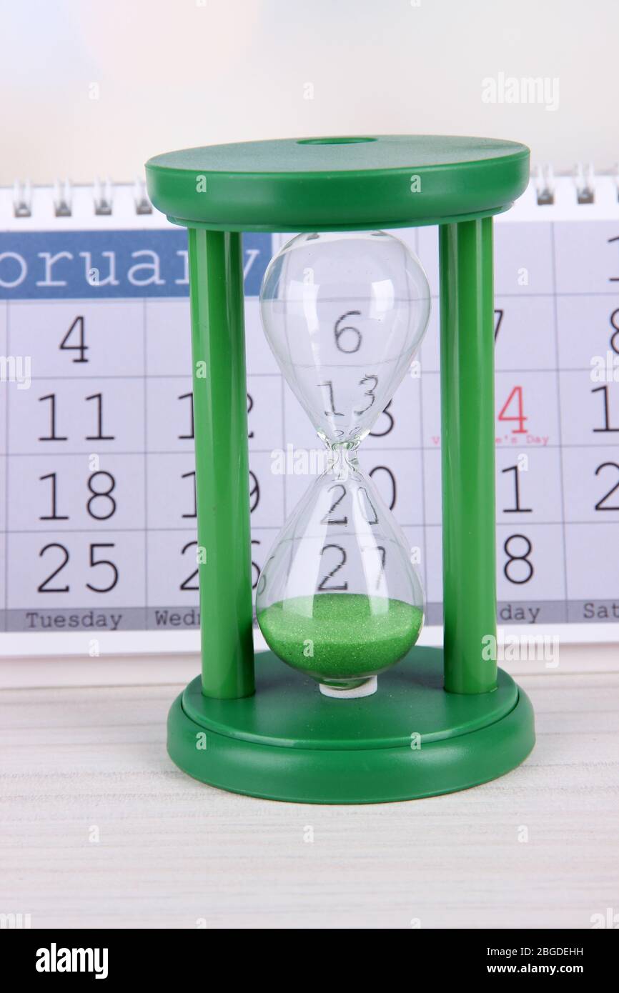 Hourglass and calendar close-up Stock Photo - Alamy