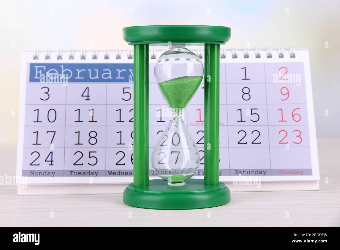 Hourglass and calendar on bright background Stock Photo - Alamy