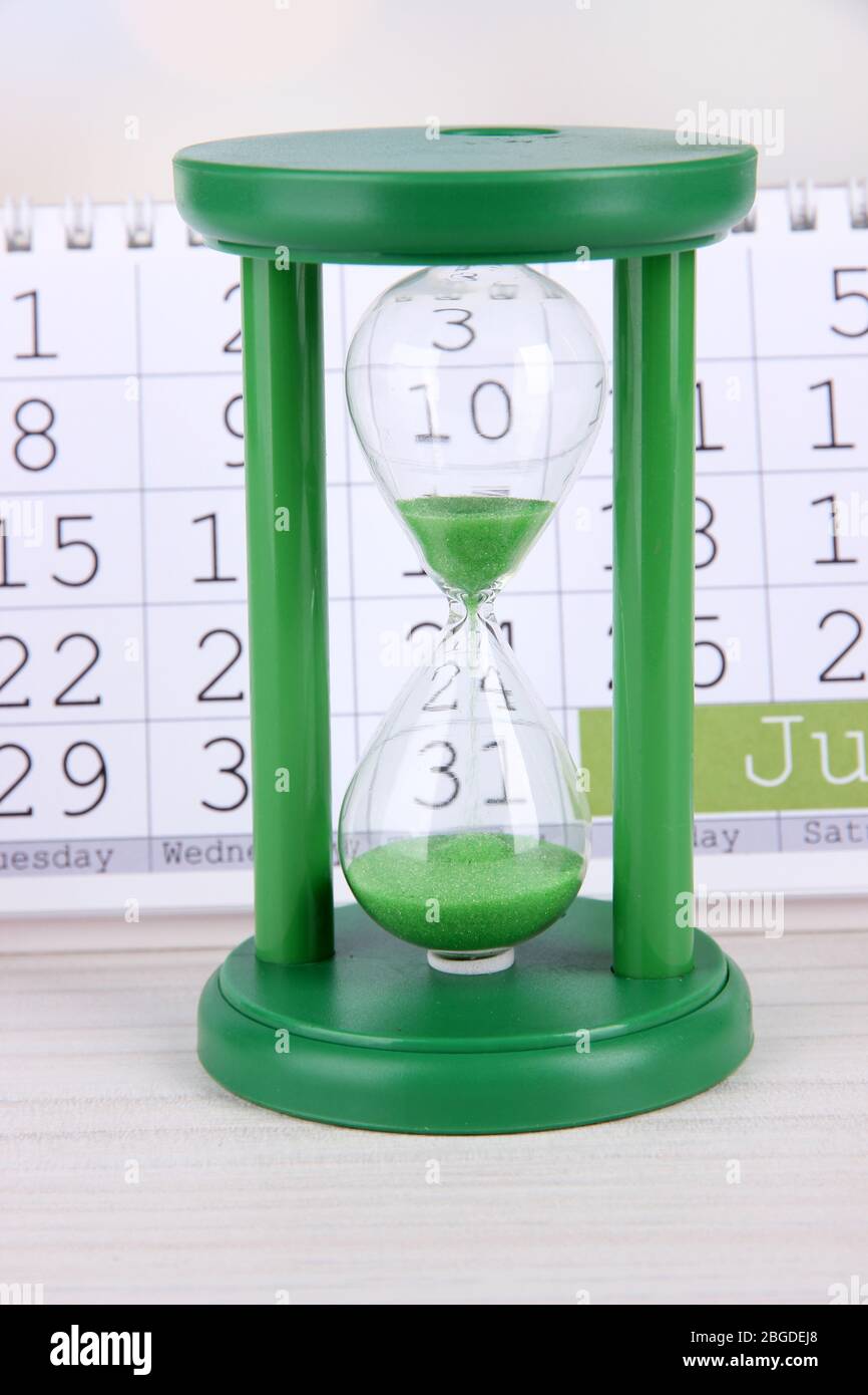 Hourglass and calendar on bright background Stock Photo - Alamy