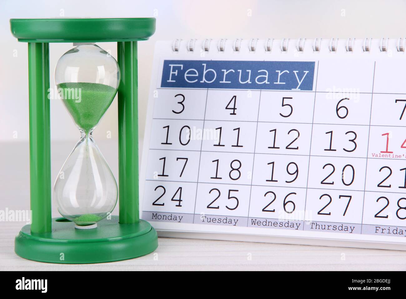 Hourglass and calendar on bright background Stock Photo - Alamy