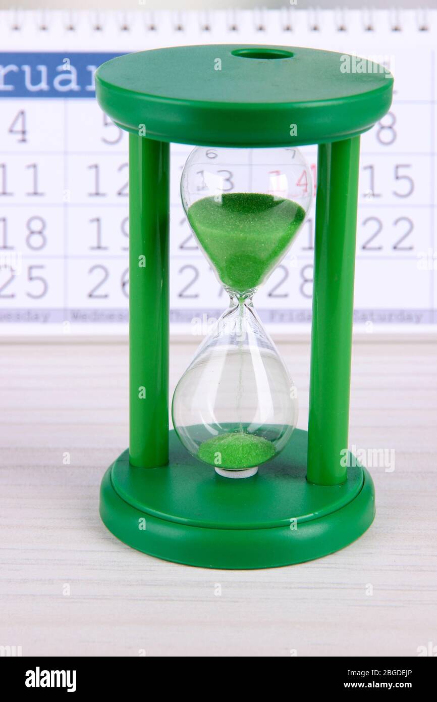 Hourglass and calendar close-up Stock Photo - Alamy