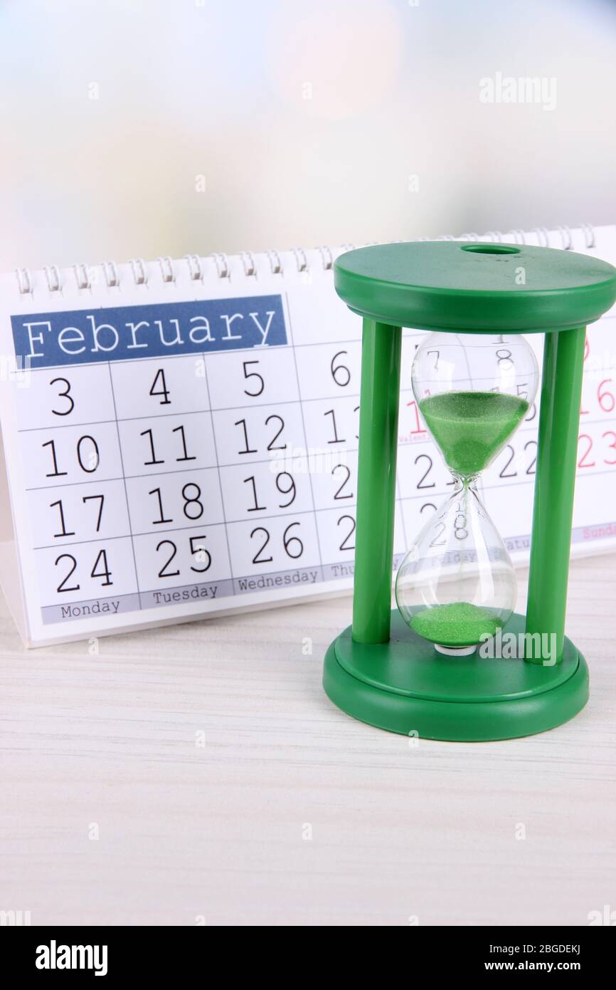 Hourglass and calendar on bright background Stock Photo - Alamy