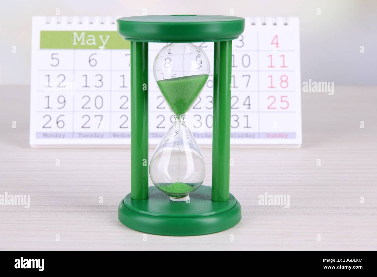 Hourglass and calendar on bright background Stock Photo - Alamy