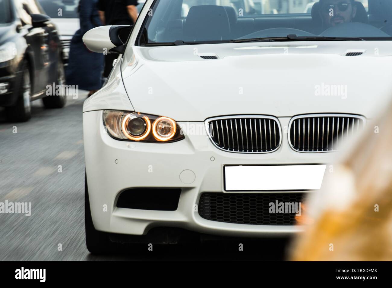 White sedan driving on the central road, waiting in the traffic lights ...