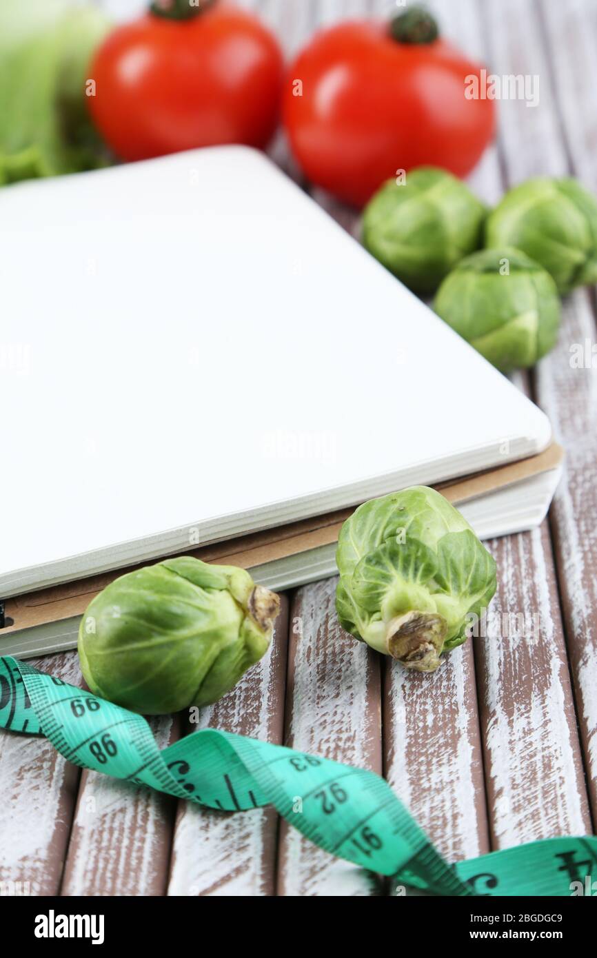 Notebook with measuring tape and vegetables on wooden background Stock ...
