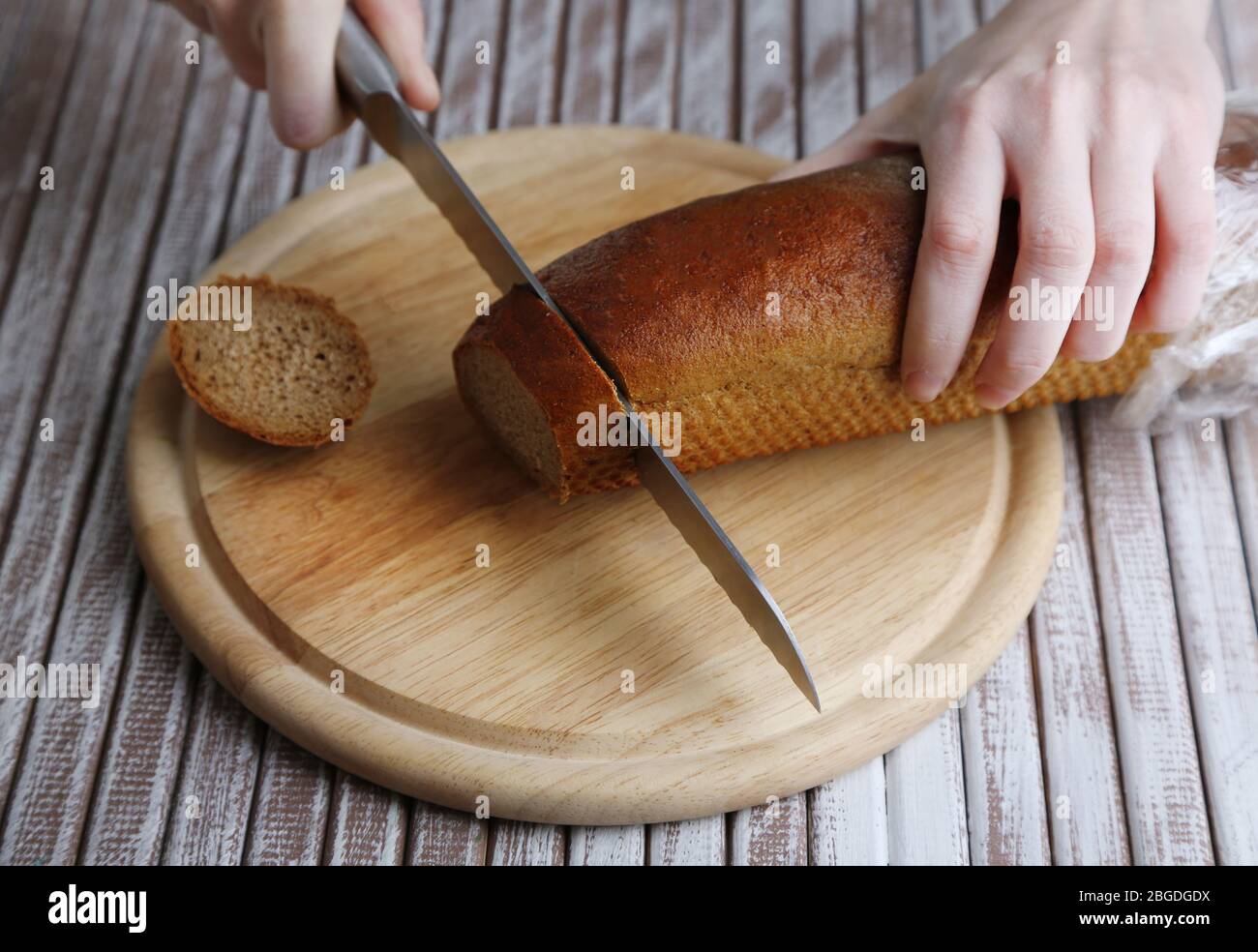Female hands cutting bread on wooden board, close-up Stock Photo - Alamy