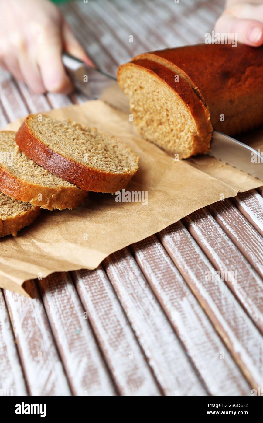 Female hands cutting bread on wooden board, close-up Stock Photo - Alamy
