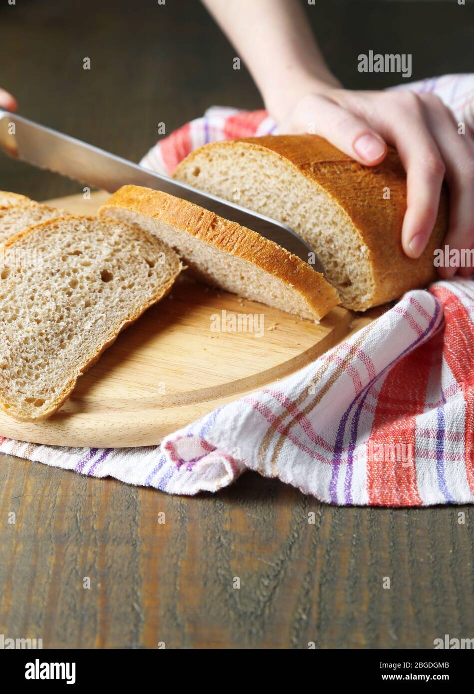 Female hands cutting bread on wooden board, close-up Stock Photo - Alamy