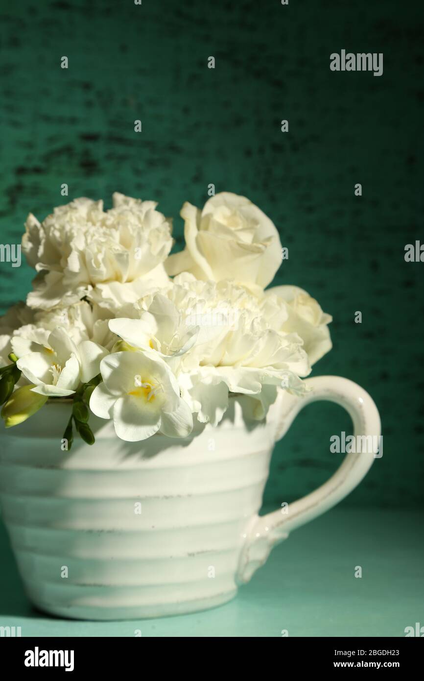 Beautiful spring flowers in cup on green background Stock Photo - Alamy