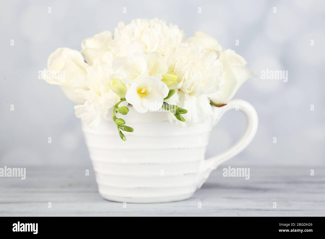 Beautiful spring flowers in cup on light background Stock Photo - Alamy