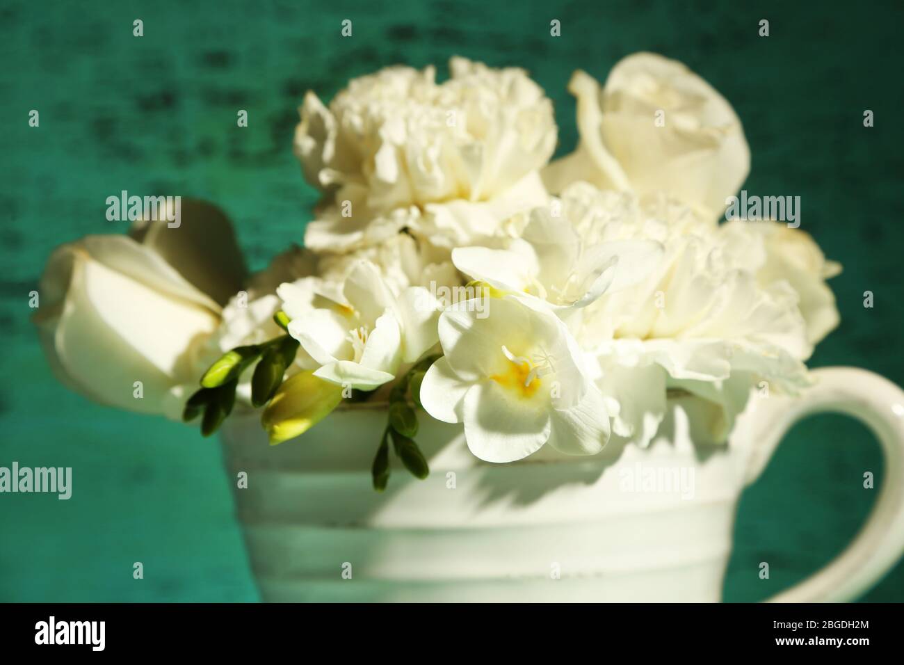 Beautiful spring flowers in cup on green background Stock Photo - Alamy