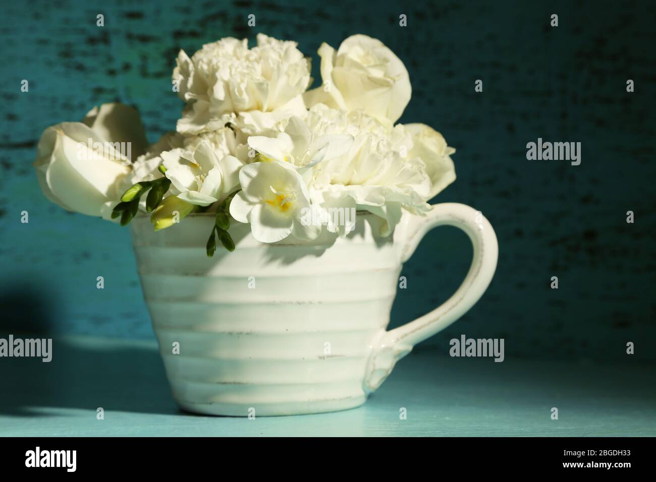 Beautiful spring flowers in cup on green background Stock Photo - Alamy
