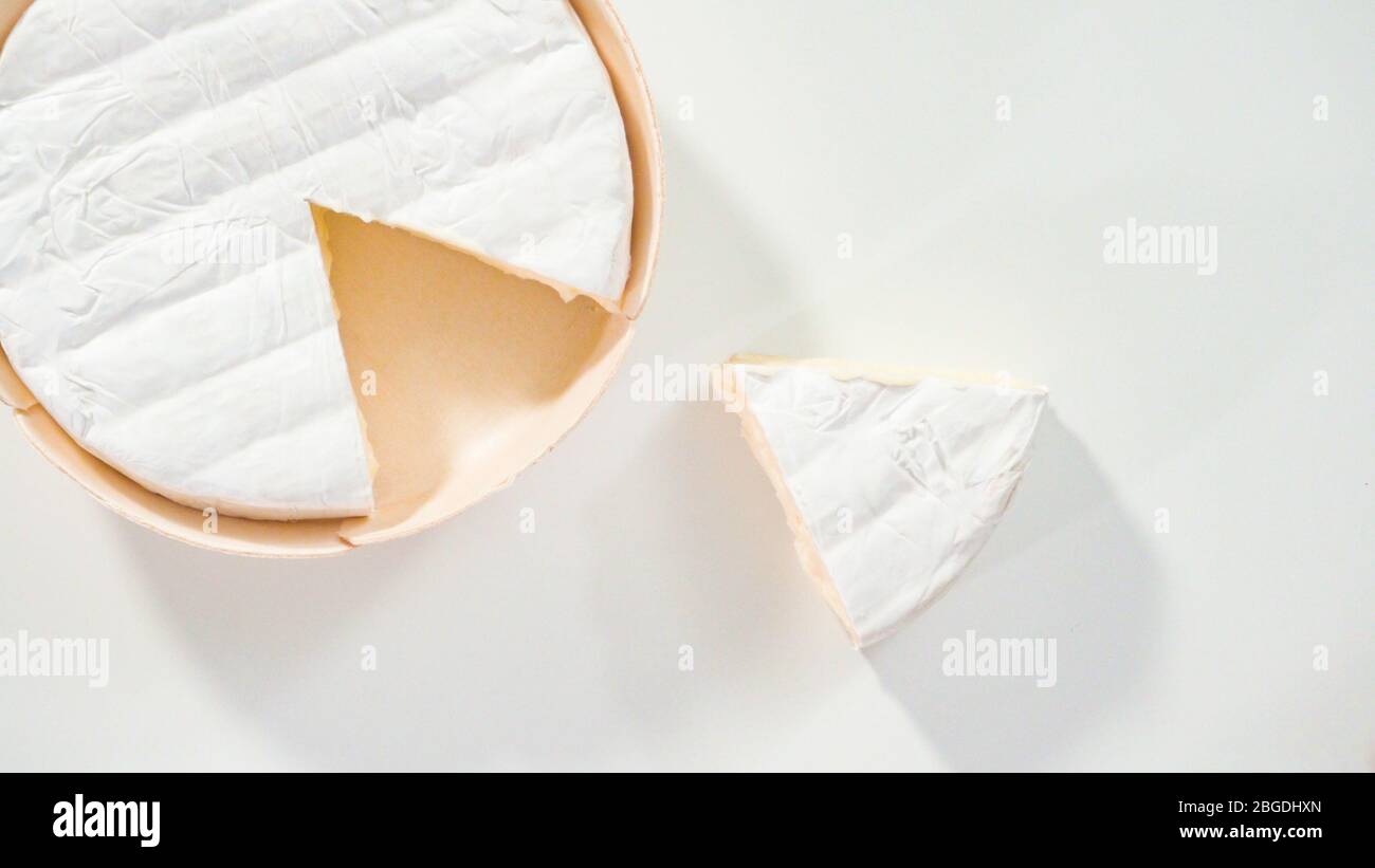 Flat lay. Slicing a large slice of gourmet cheese on a white background ...