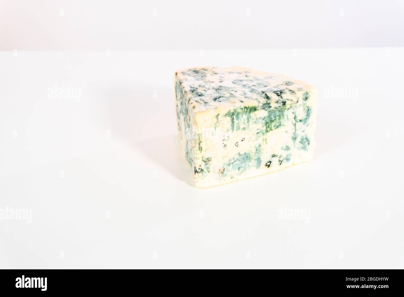 Large slice of blue cheese on a white background Stock Photo - Alamy