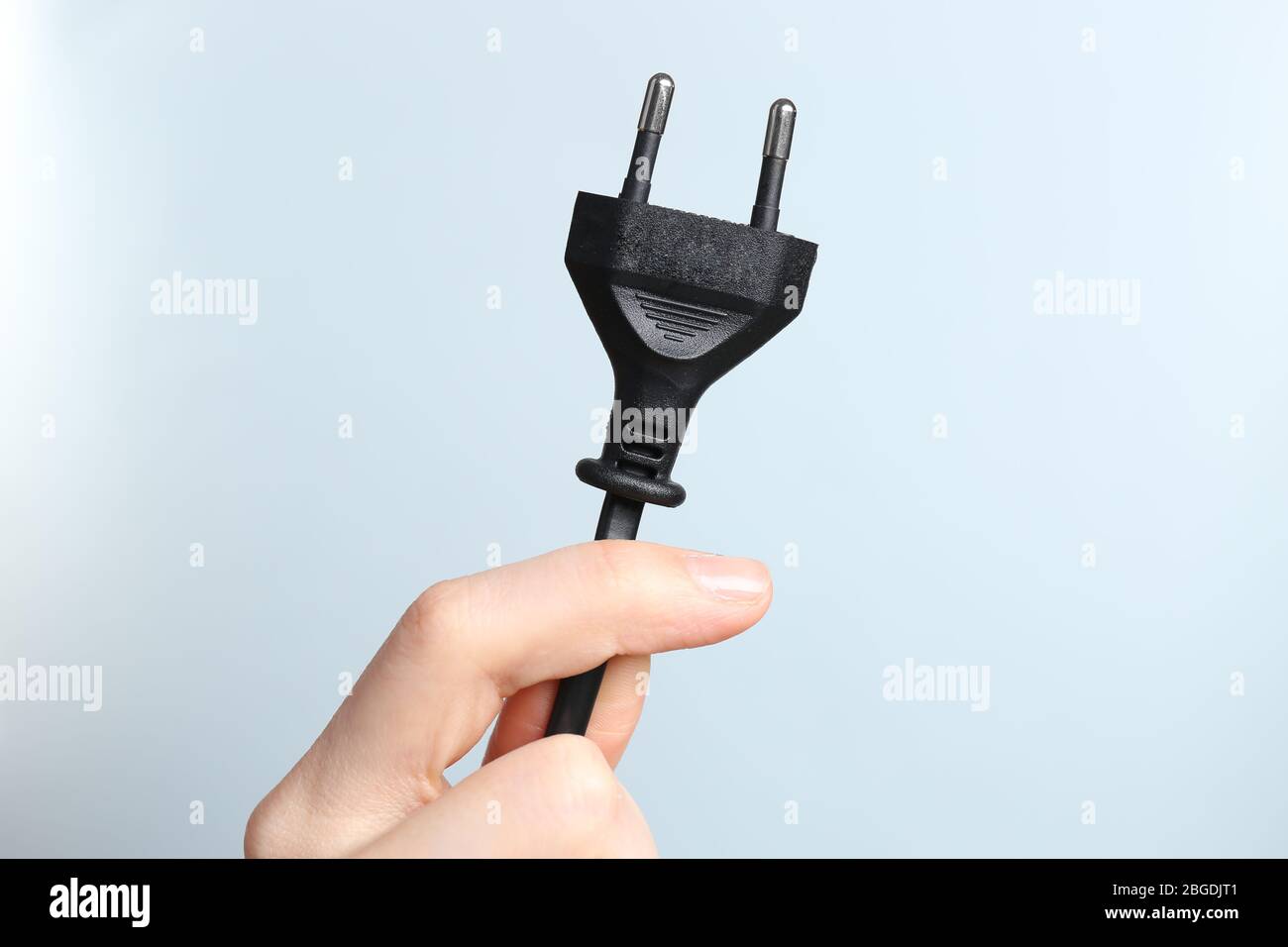 Hand holding electric plug on blue background Stock Photo - Alamy