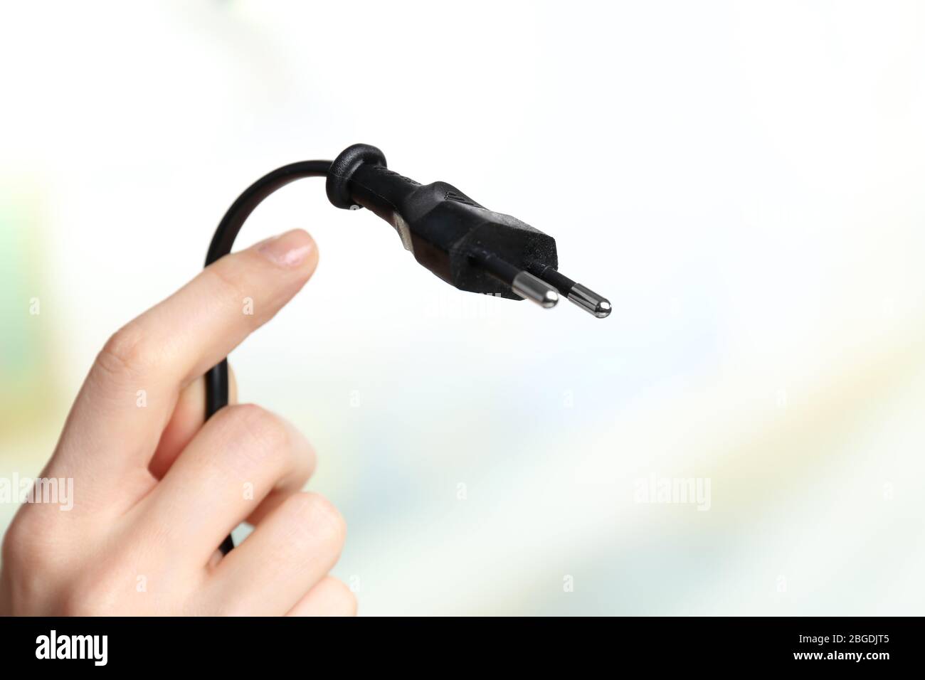Hand holding electric plug on light background Stock Photo - Alamy