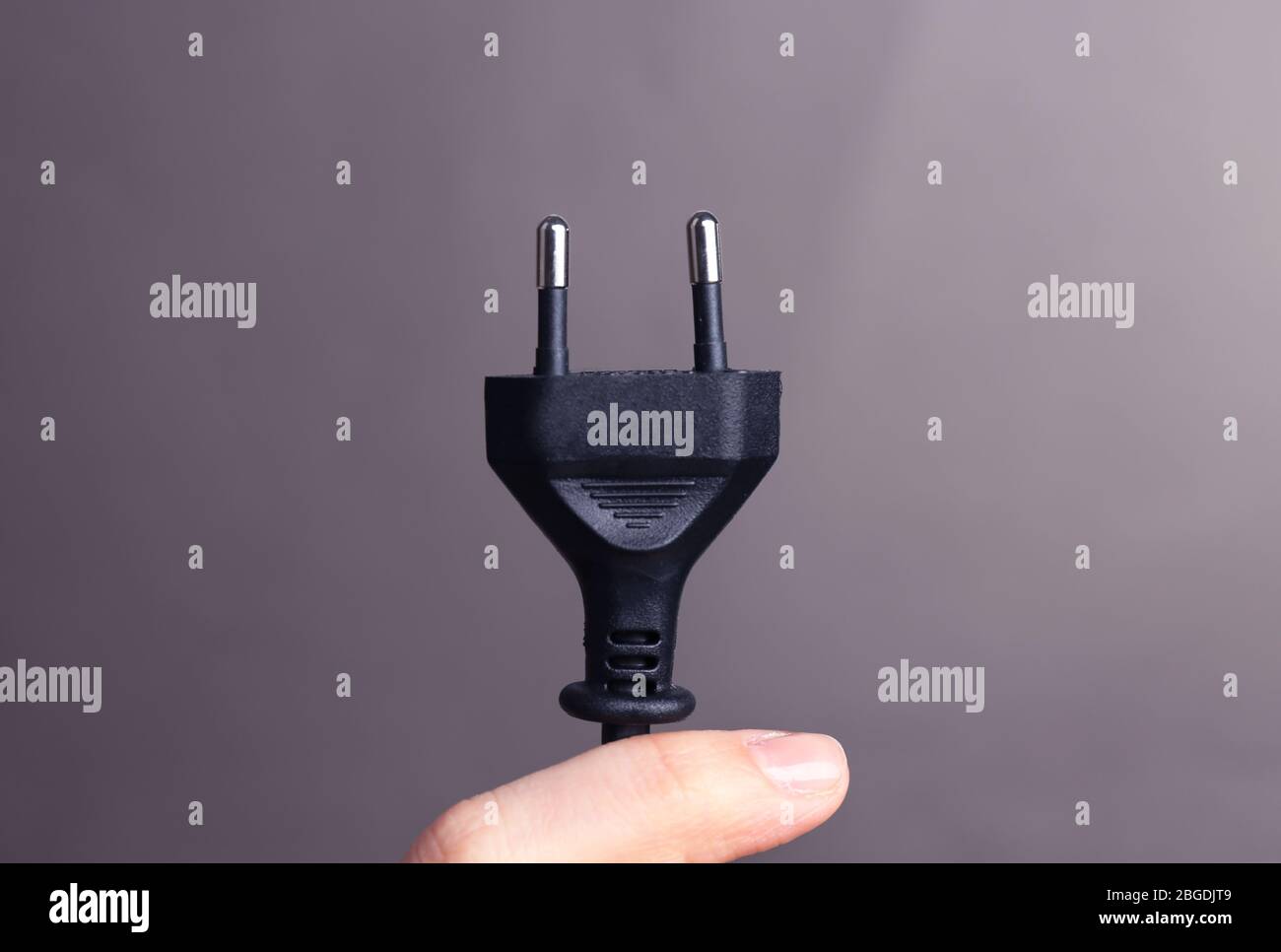 Hand holding electric plug on grey background Stock Photo - Alamy