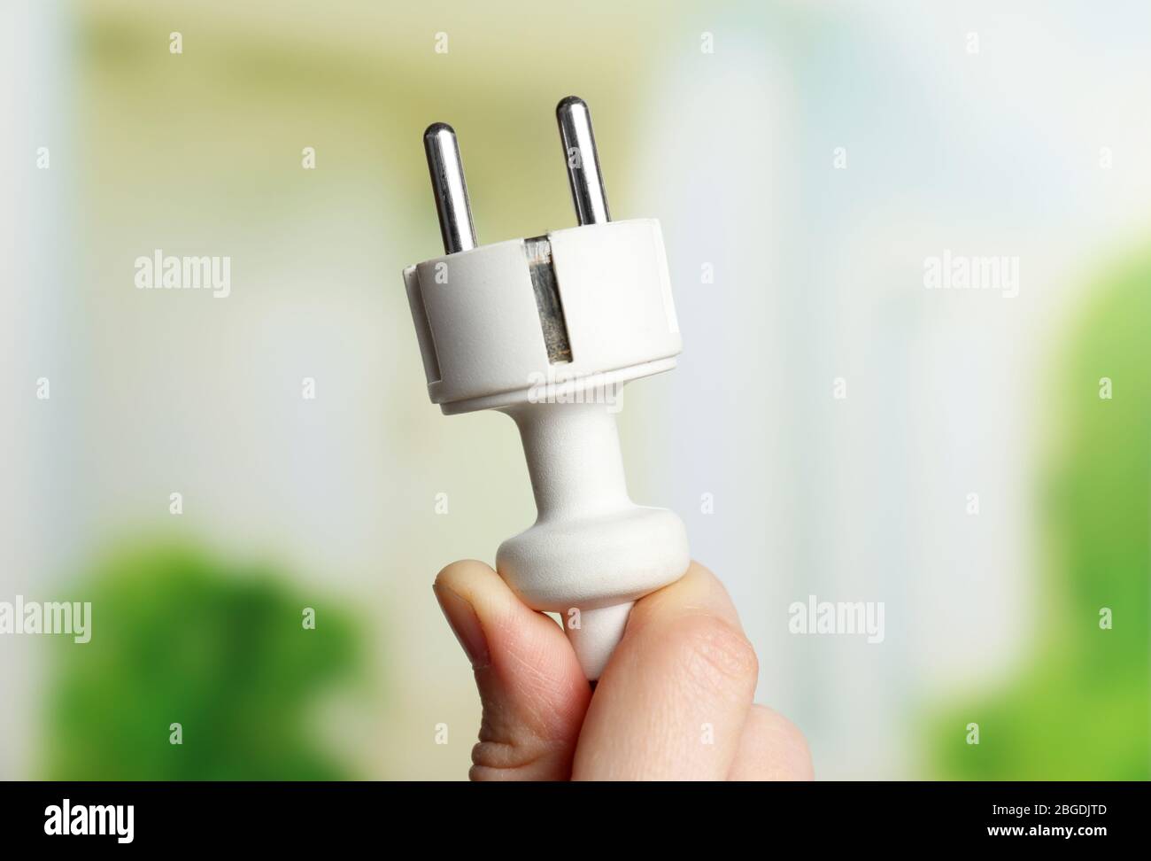 Hand holding electric plug on nature background Stock Photo - Alamy