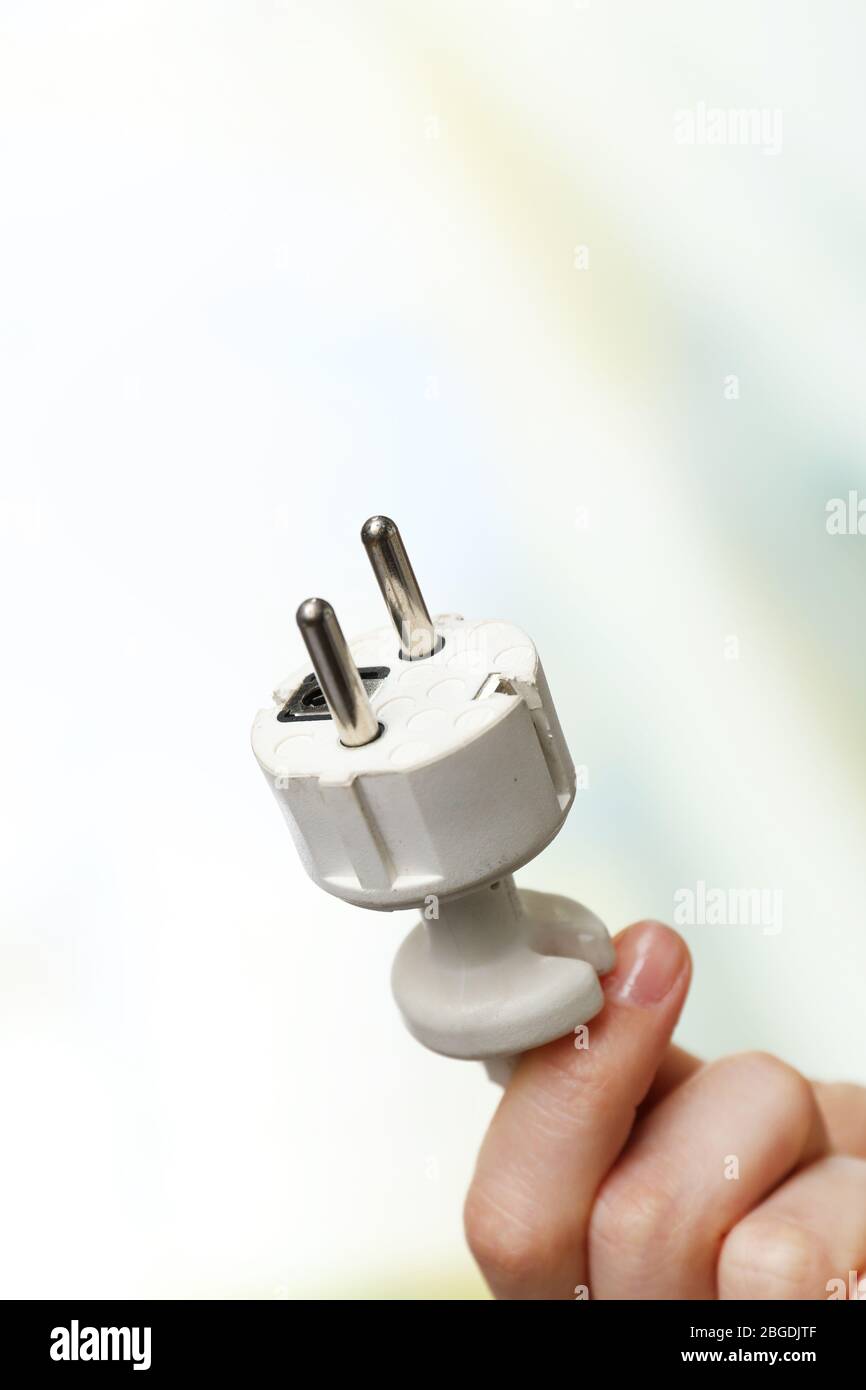 Hand holding electric plug on light background Stock Photo - Alamy