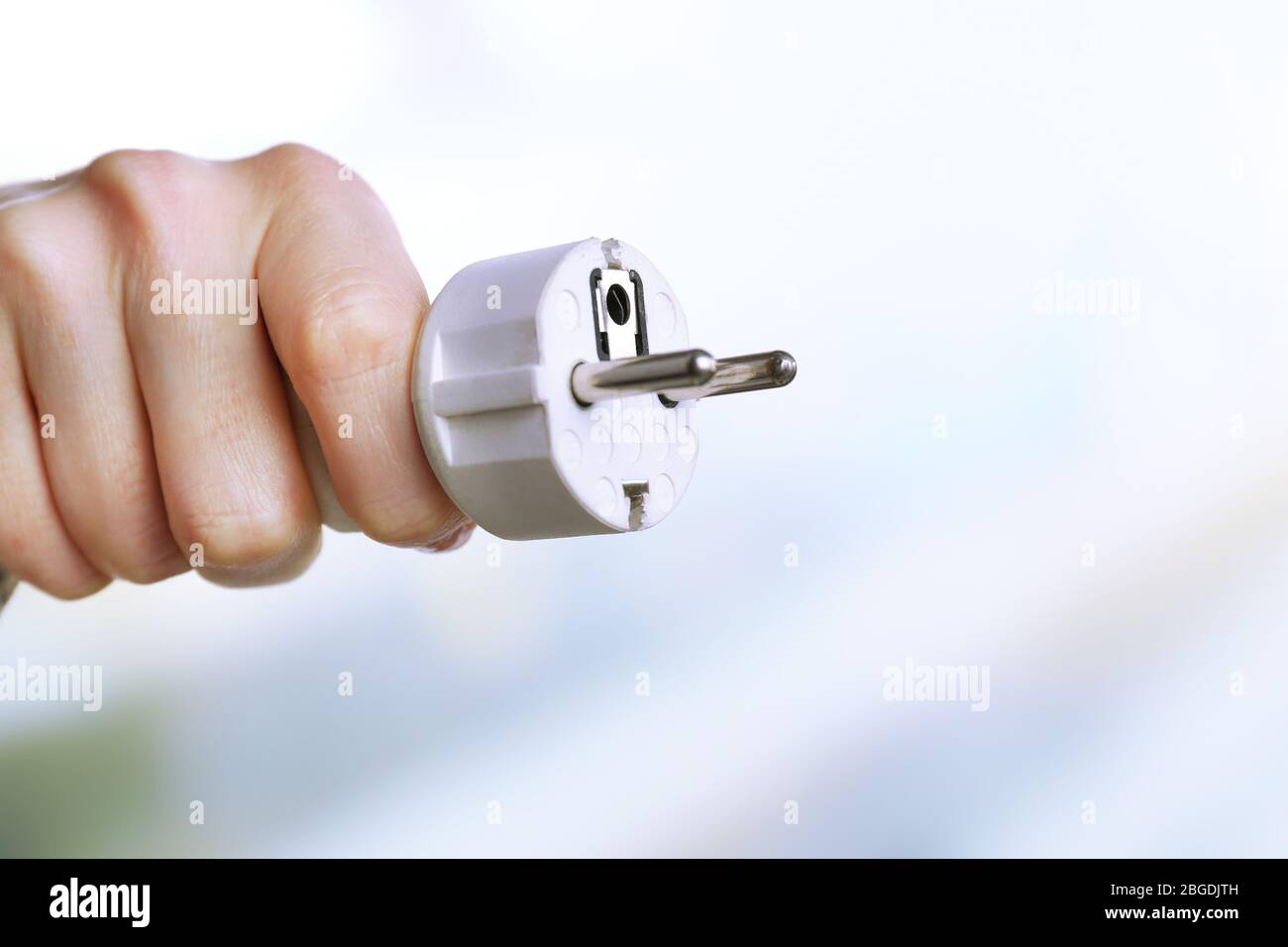 Hand holding electric plug on light background Stock Photo - Alamy