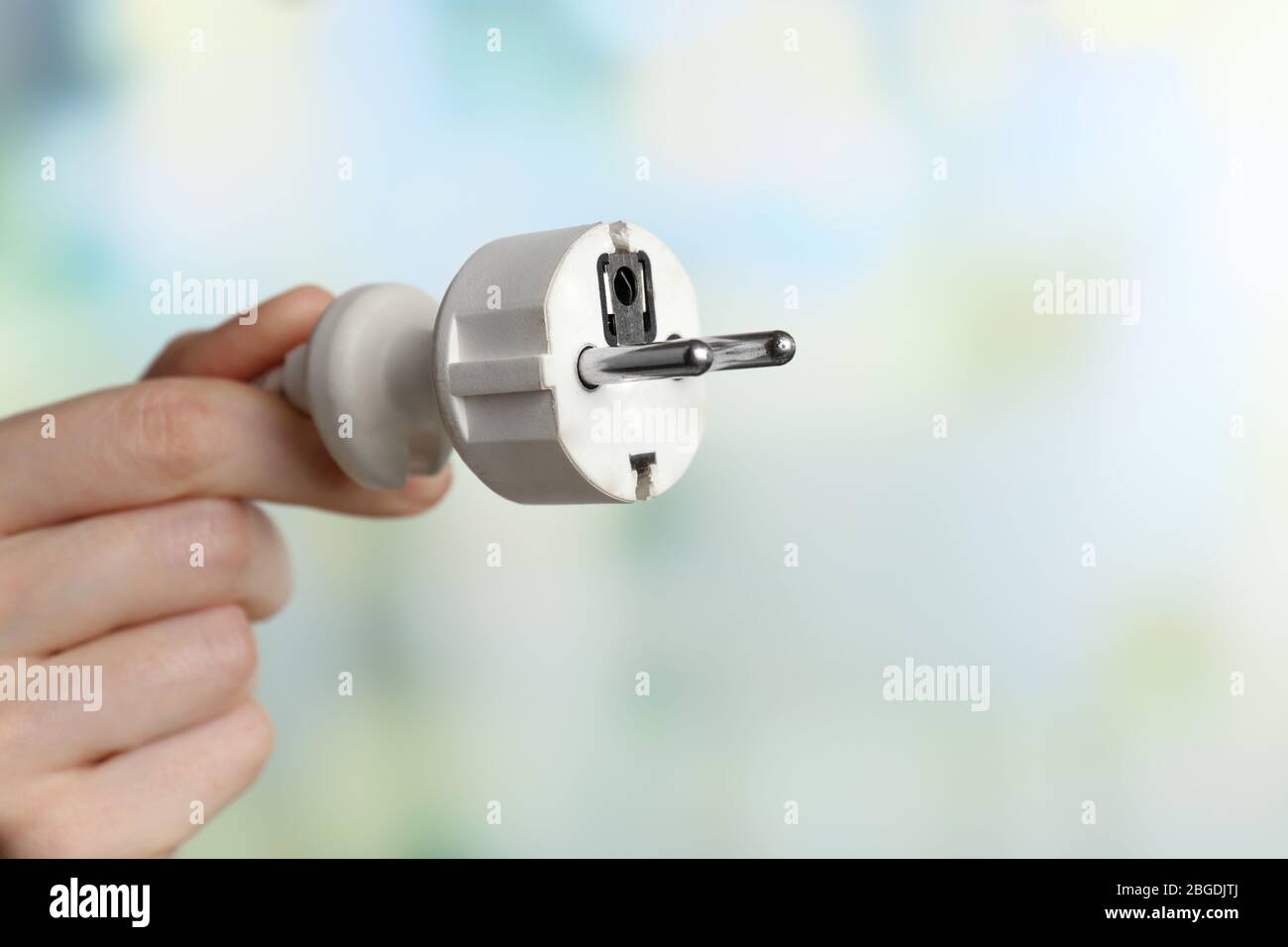 Hand holding electric plug on light background Stock Photo - Alamy