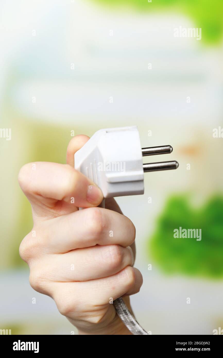 Hand holding electric plug on nature background Stock Photo - Alamy