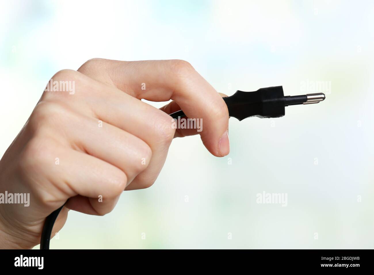 Hand holding electric plug on light background Stock Photo - Alamy