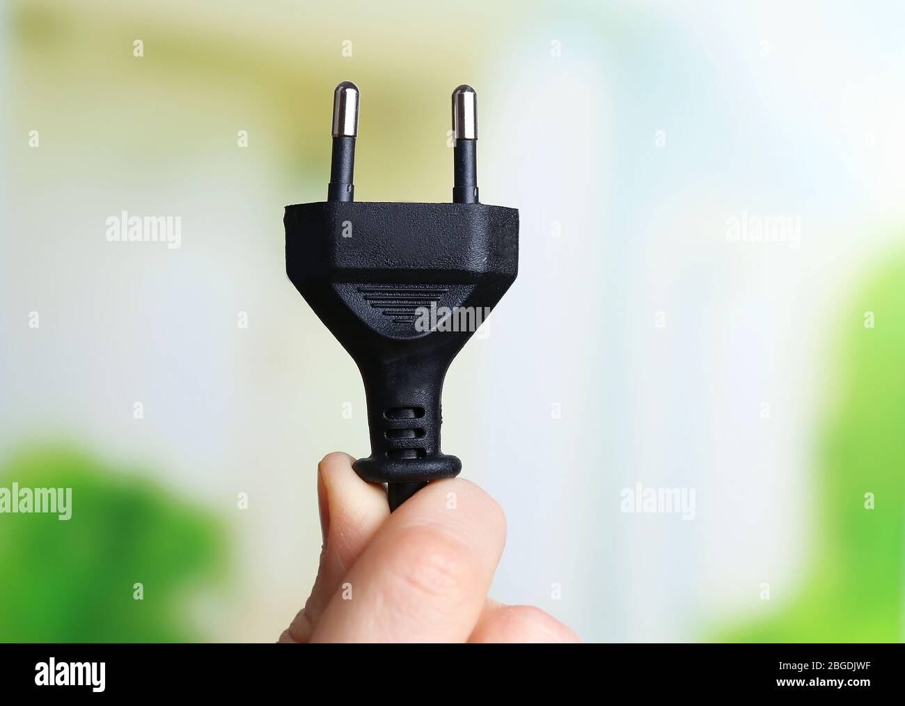 Hand holding electric plug on nature background Stock Photo - Alamy