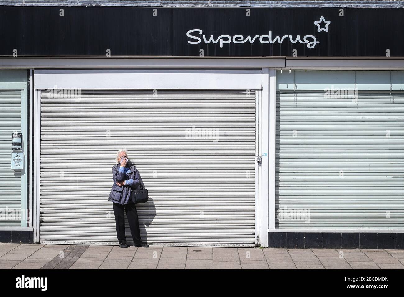 Older lady using an improvised face mask whilst standing against the ...