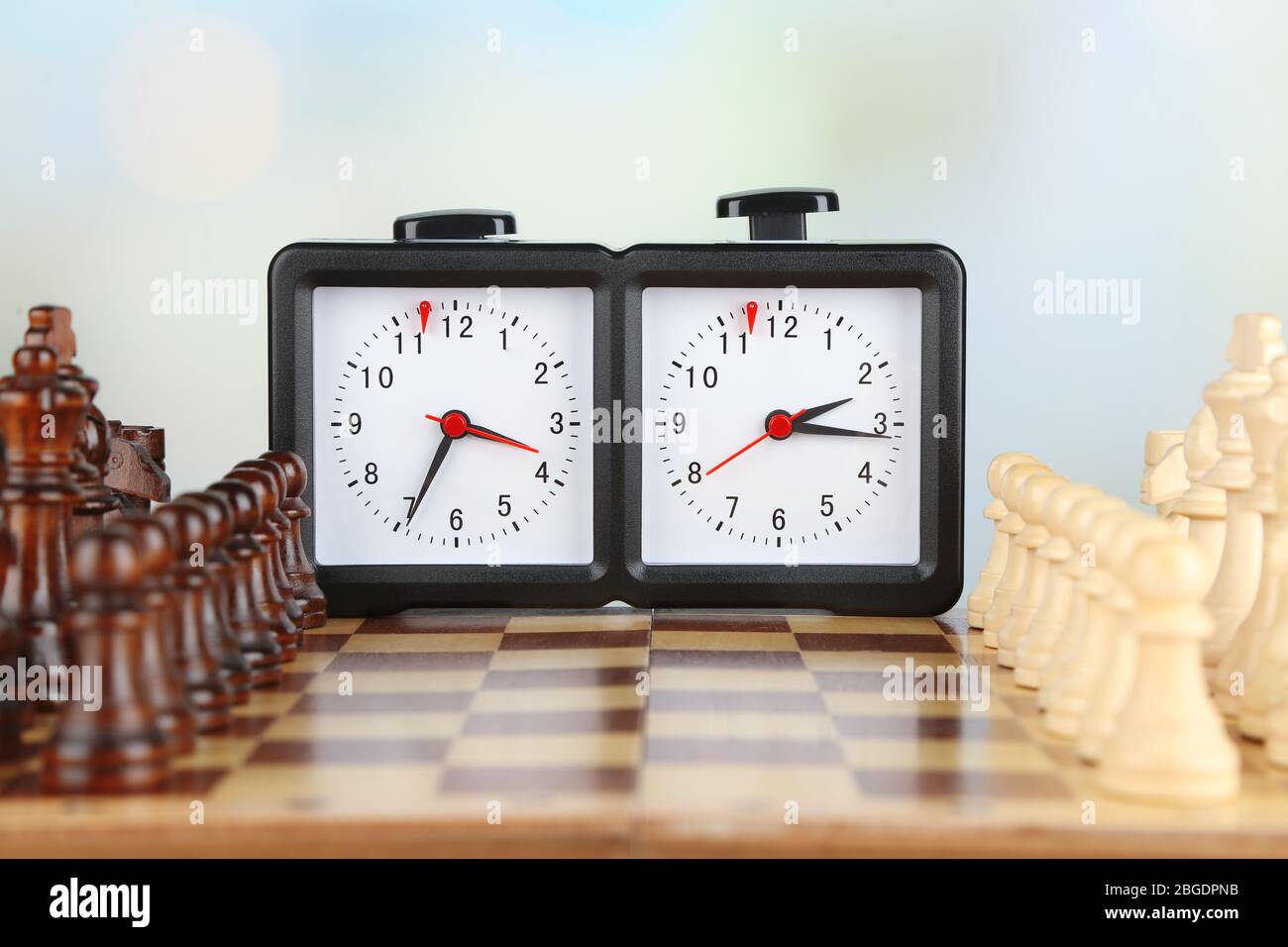 Chessboard with chess and clock on light background Stock Photo - Alamy