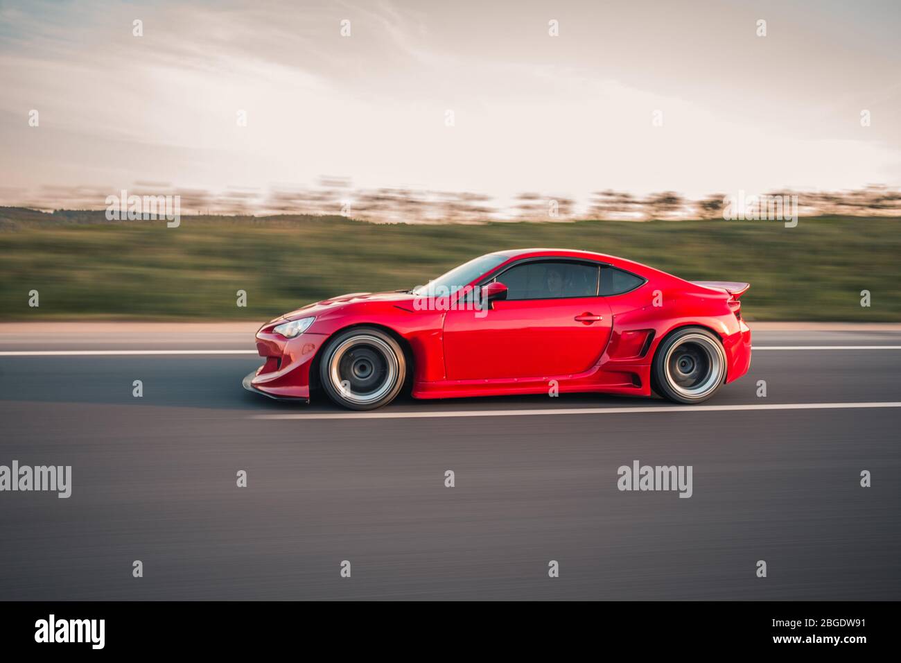 Red racing car on the vast grand highway with panoramic view, profile ...
