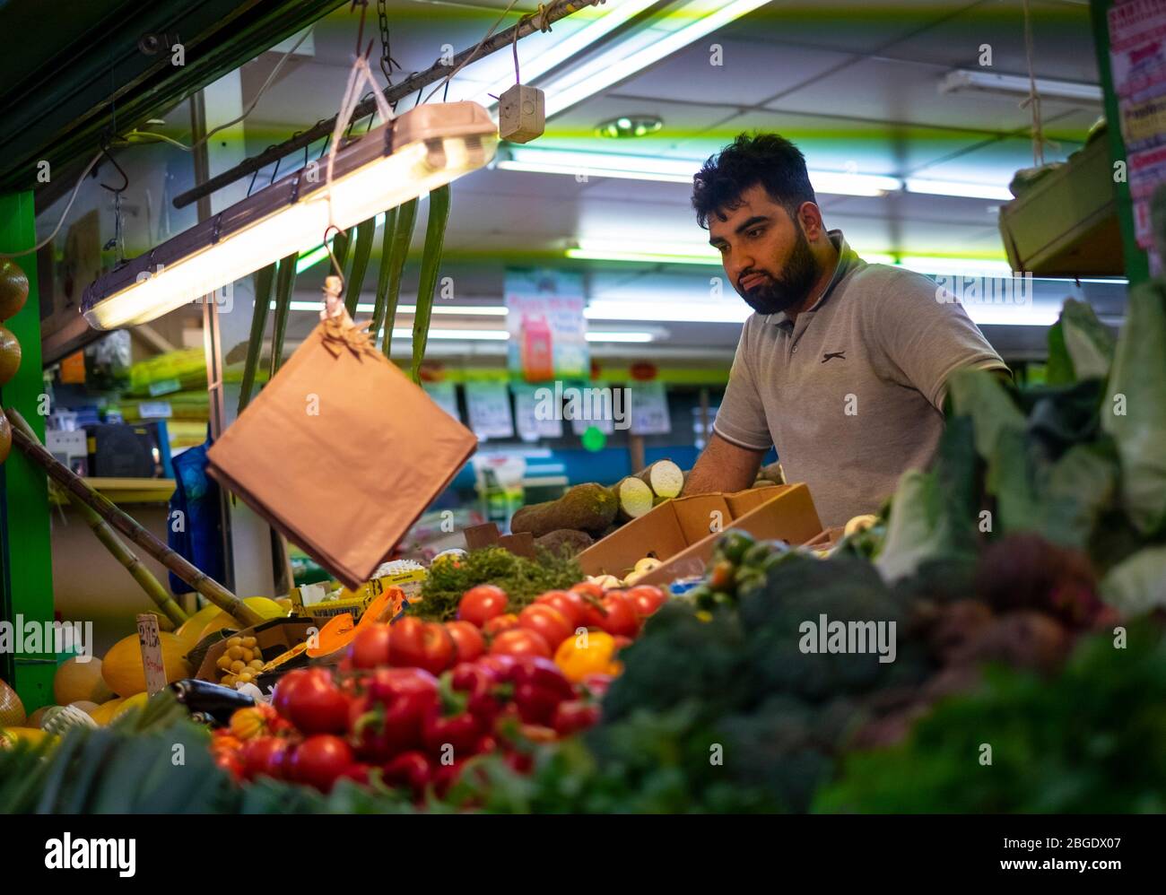 A male vendor standing beside his fruit and vegetable produce in ...