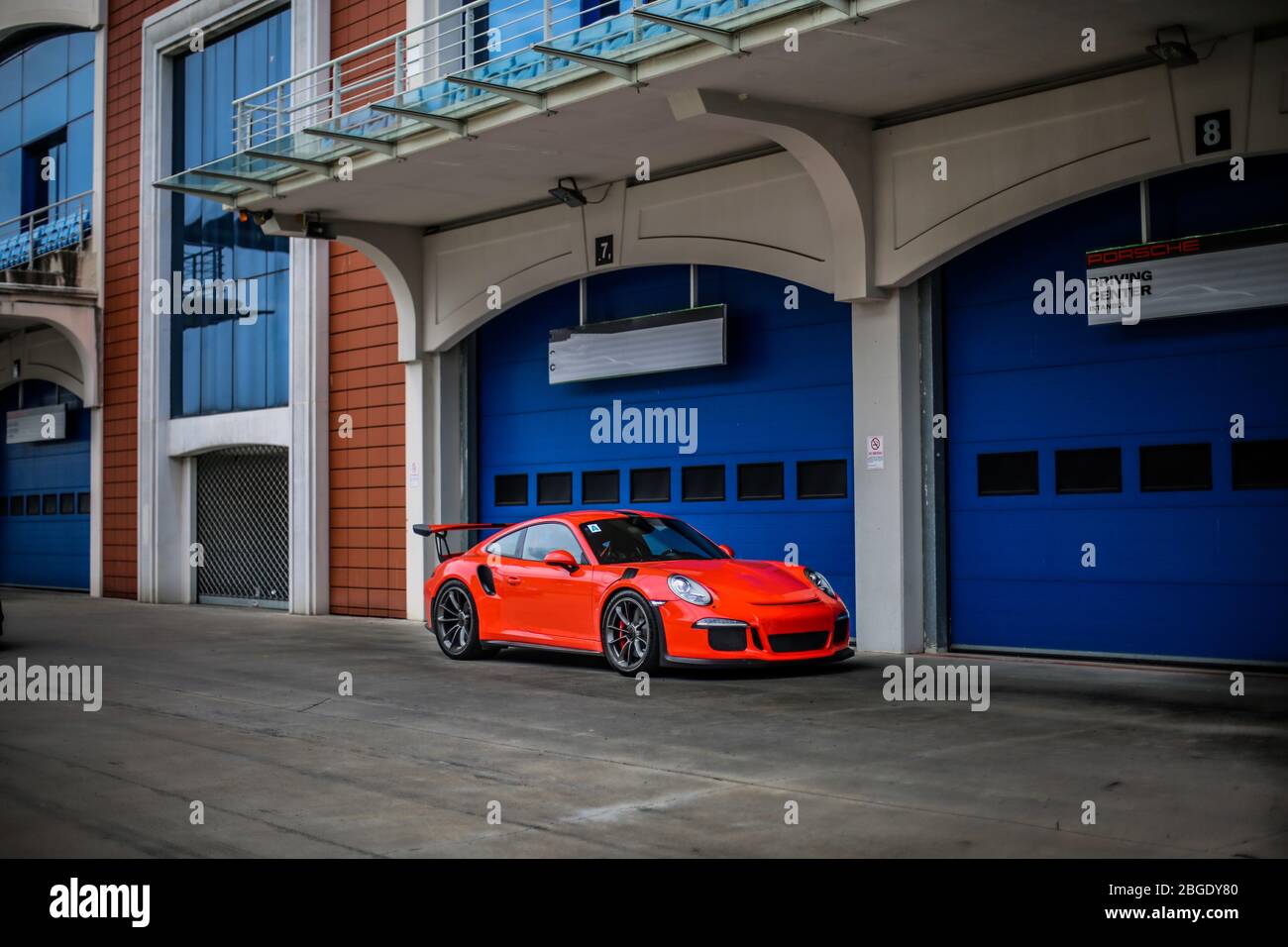 Orange color racing cars on the rally track in front of the gates of a ...