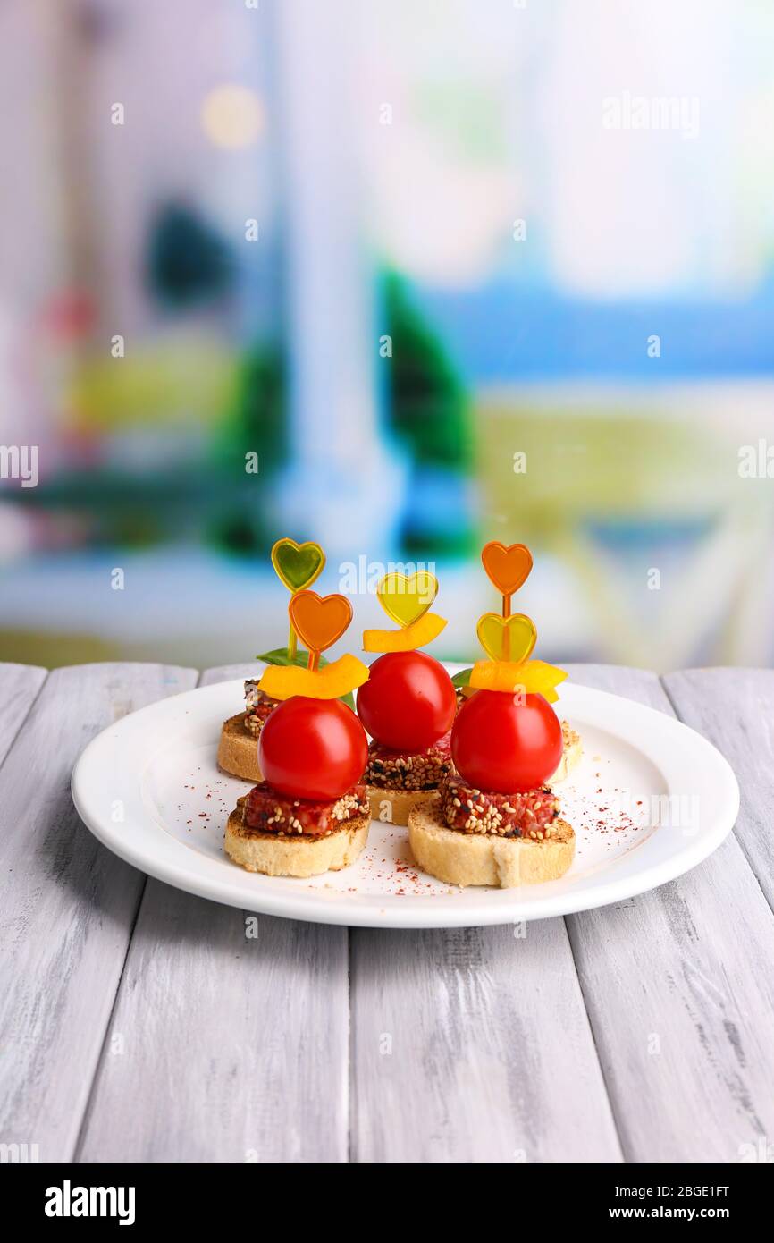 Tasty canapes with salami,tomato, pepper and basil leaves, on plate, on ...
