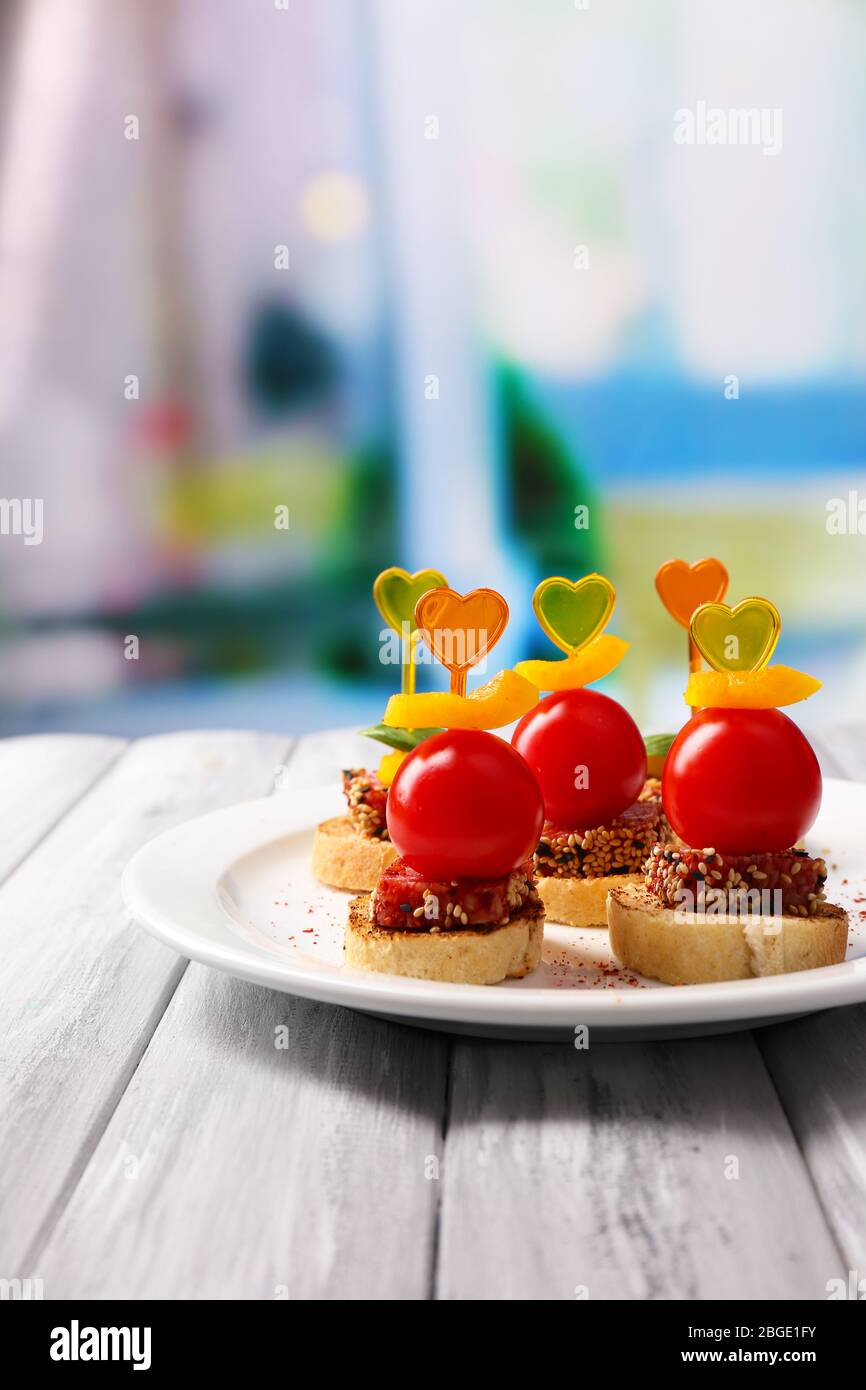 Tasty canapes with salami,tomato, pepper and basil leaves, on plate, on ...