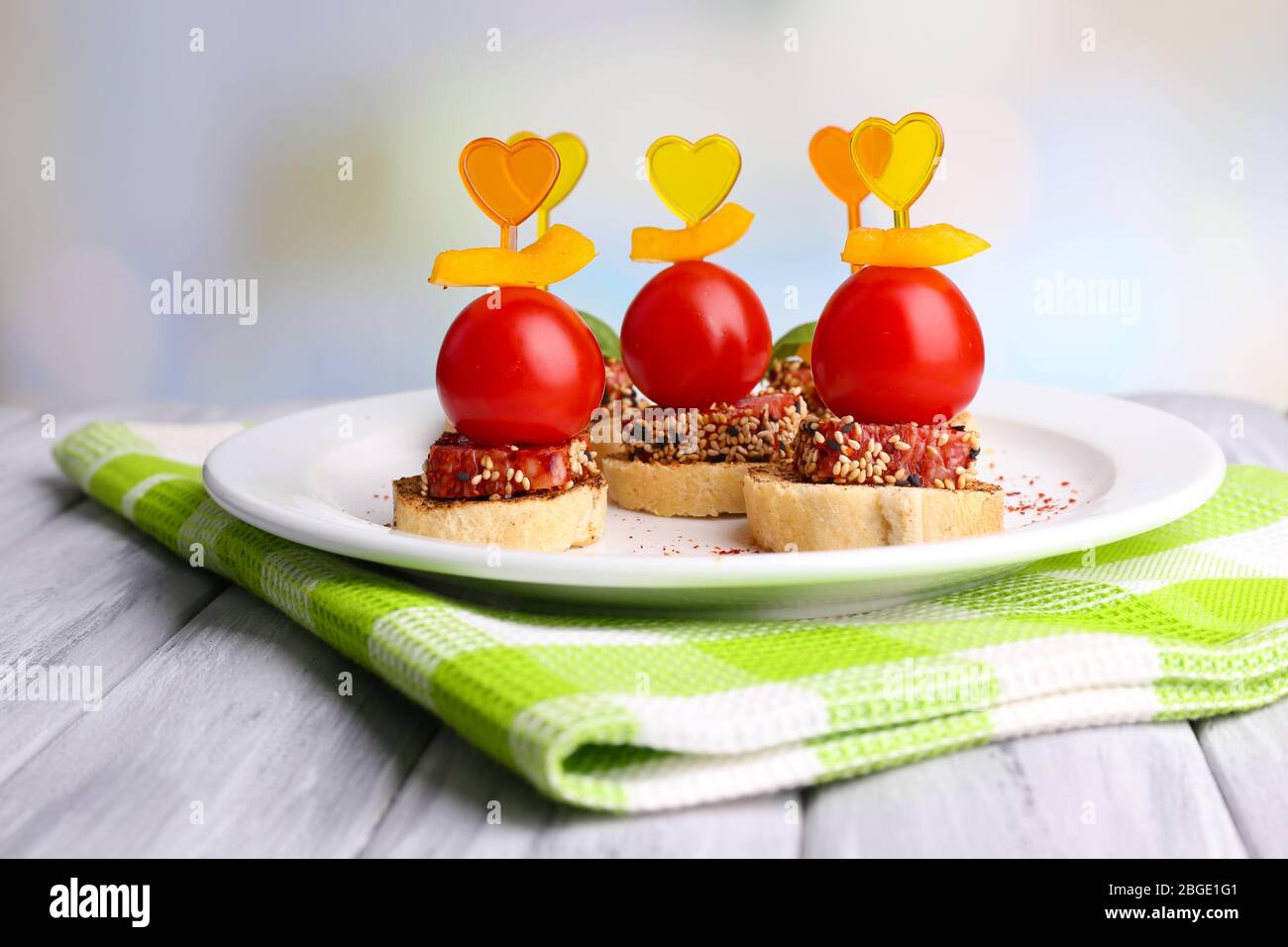 Tasty canapes with salami,tomato, pepper and basil leaves, on plate, on ...