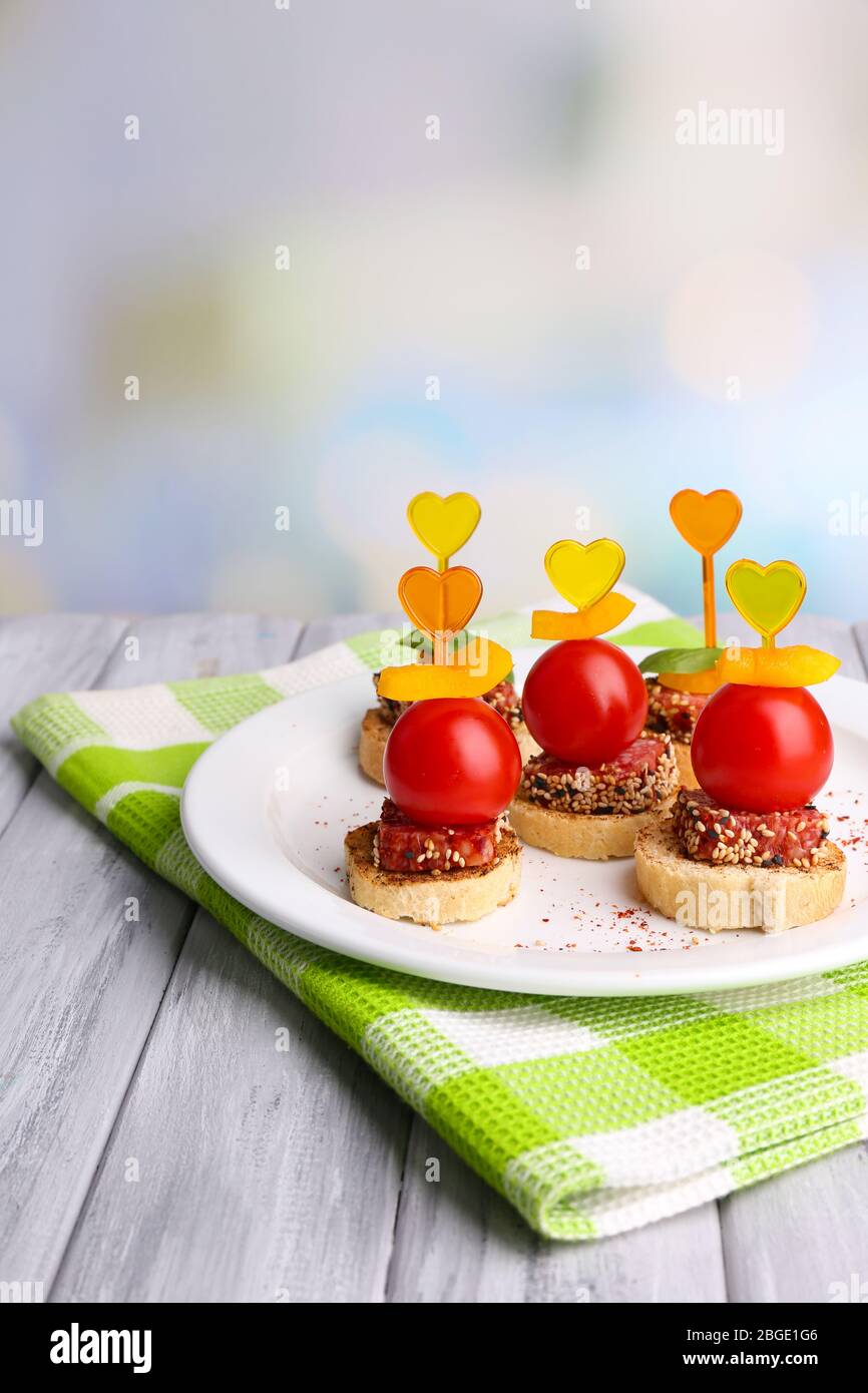 Tasty canapes with salami,tomato, pepper and basil leaves, on plate, on ...